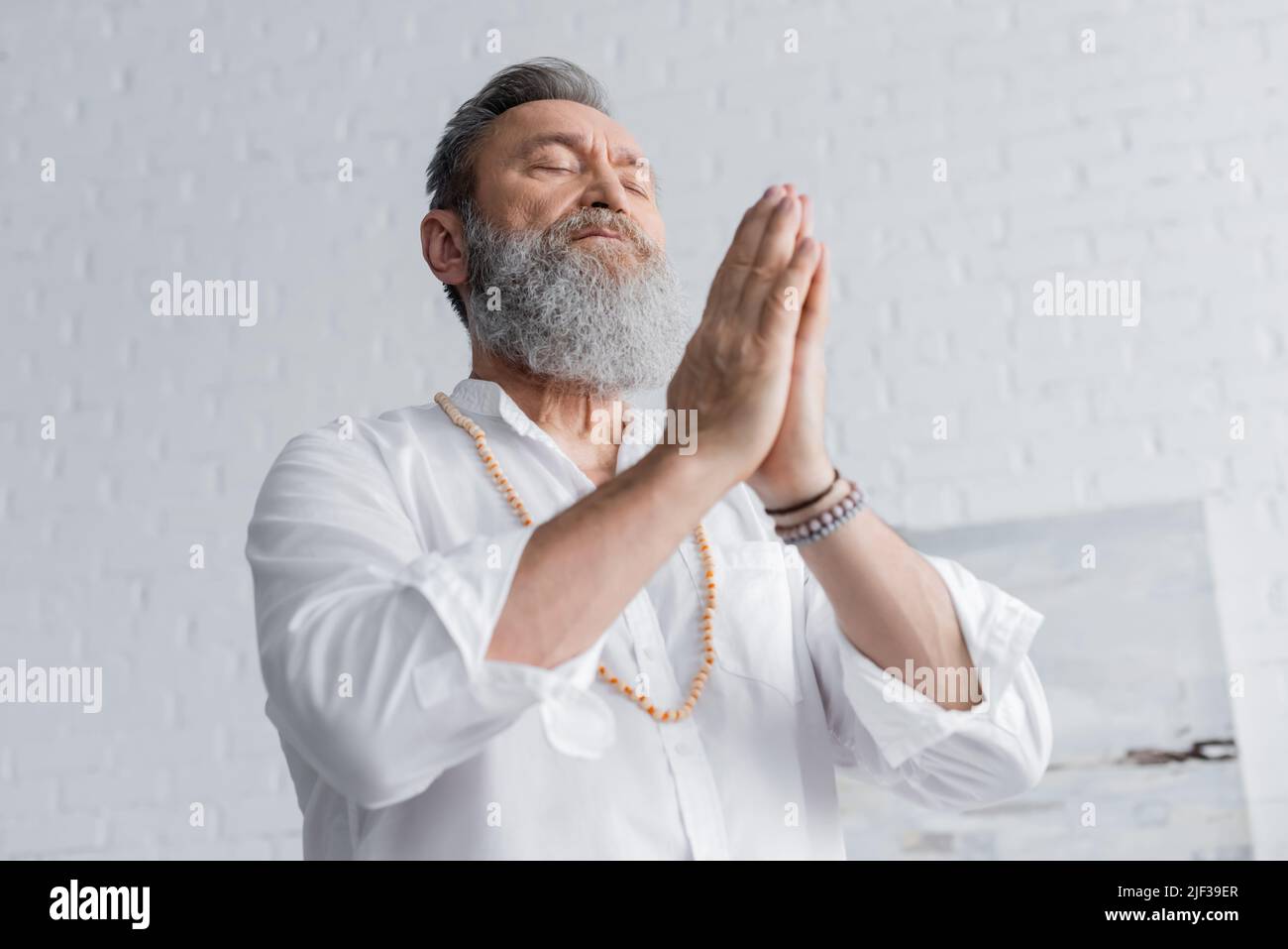 low angle view of bearded guru man meditating with closed eyes and ...