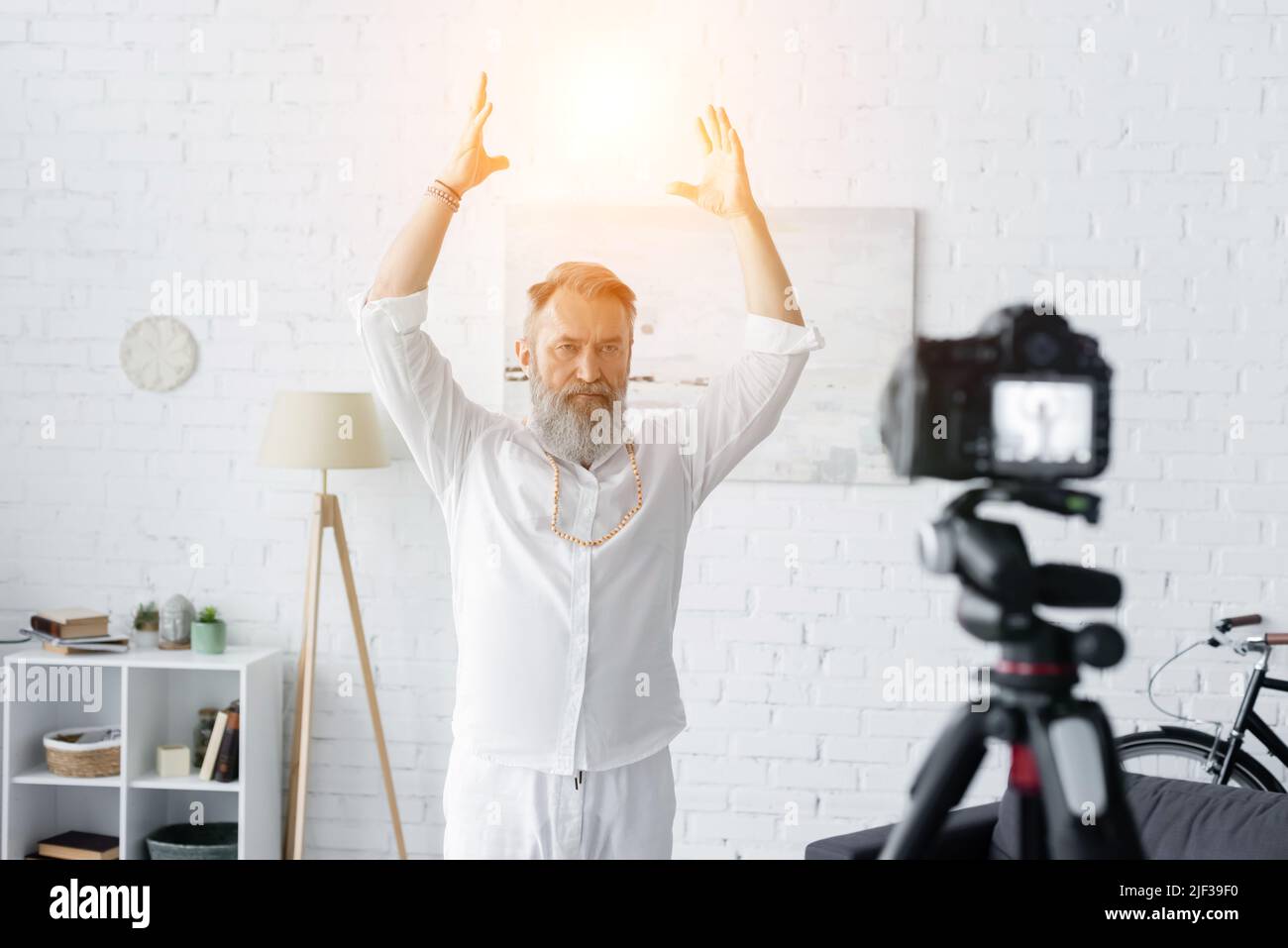 spiritual guru with raised hands near shining aura and blurred digital ...