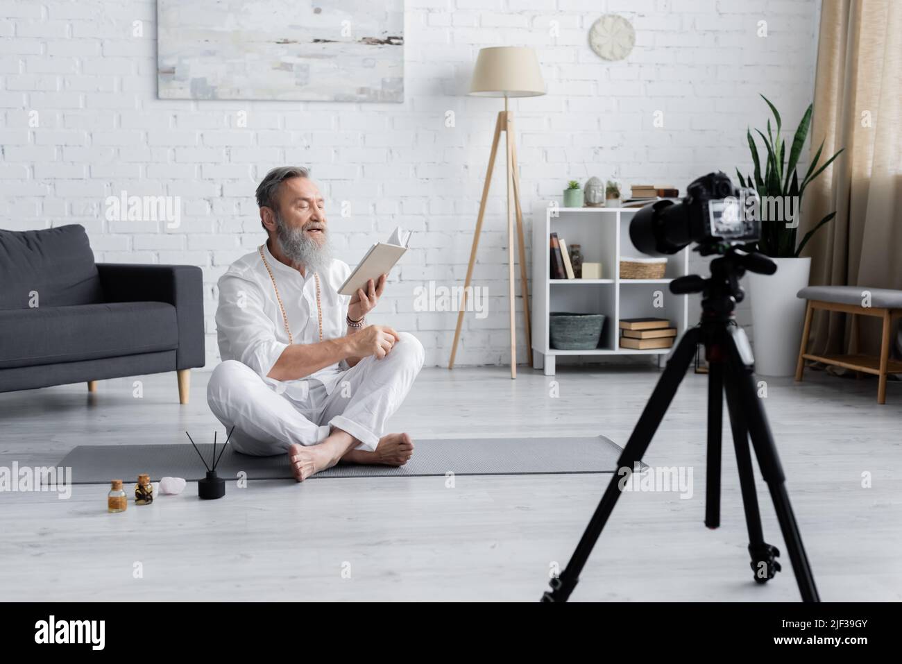 yoga master reading manual while sitting in easy pose near essential ...