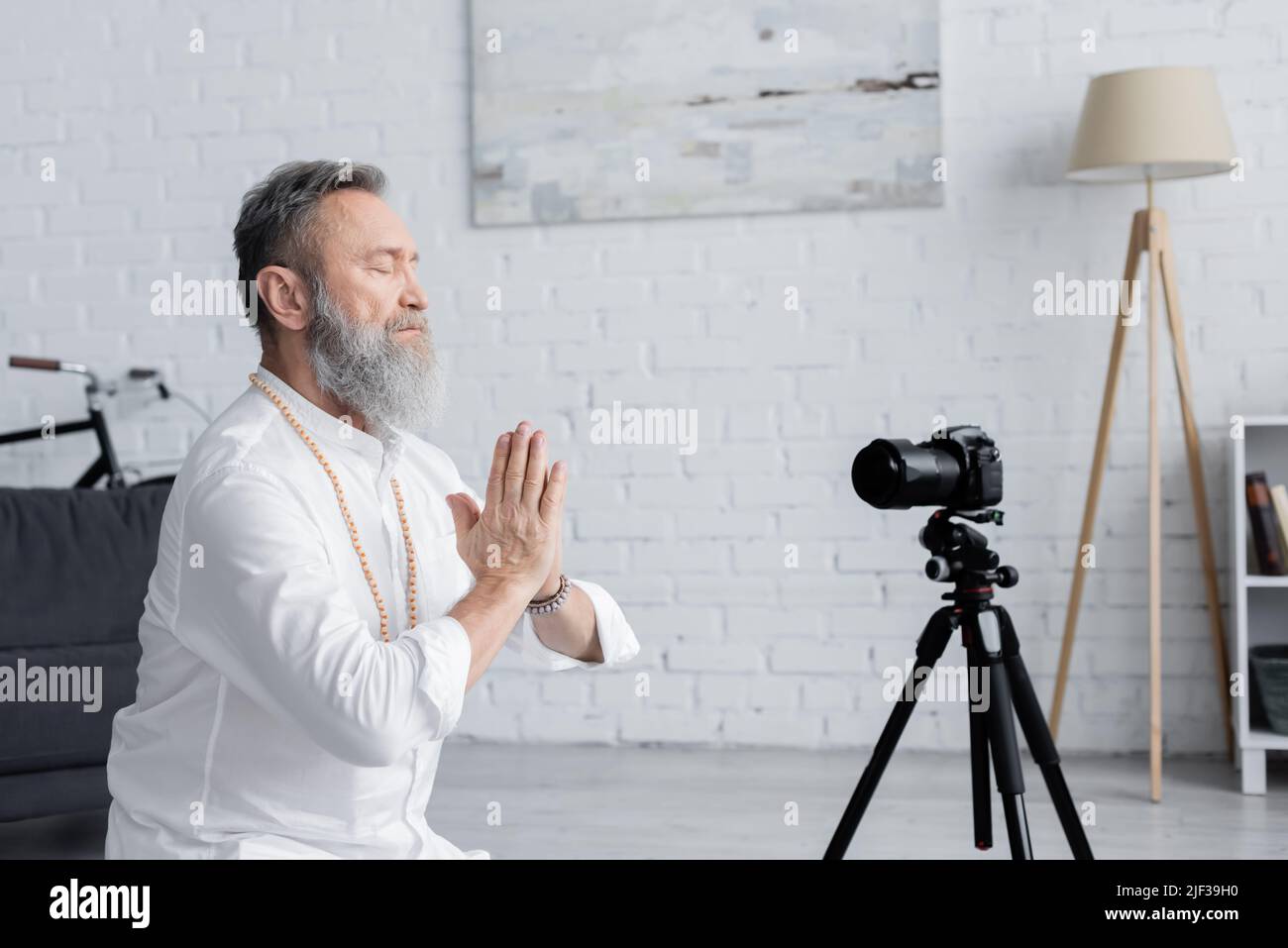 mastermind guru meditating with closed eyes and praying hands near ...