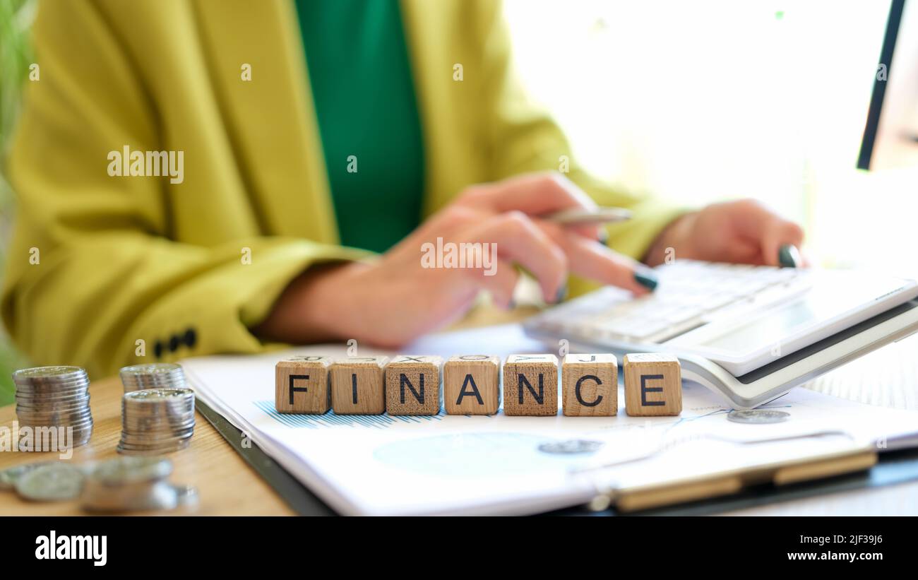 Finance text on cubes and working businesswoman with calculator Stock ...