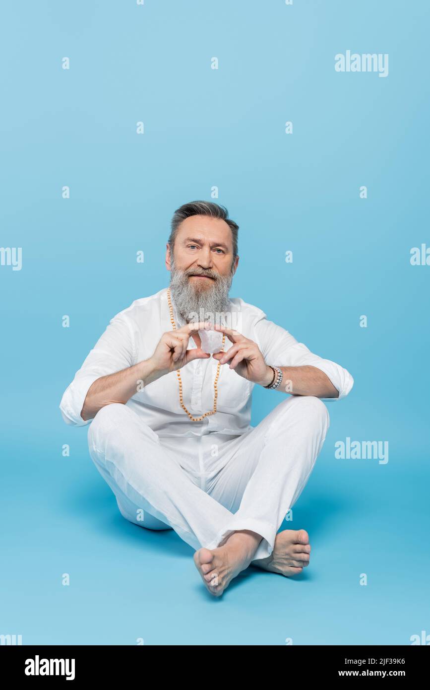 senior guru tutor showing hakini mudra while sitting with crossed legs ...