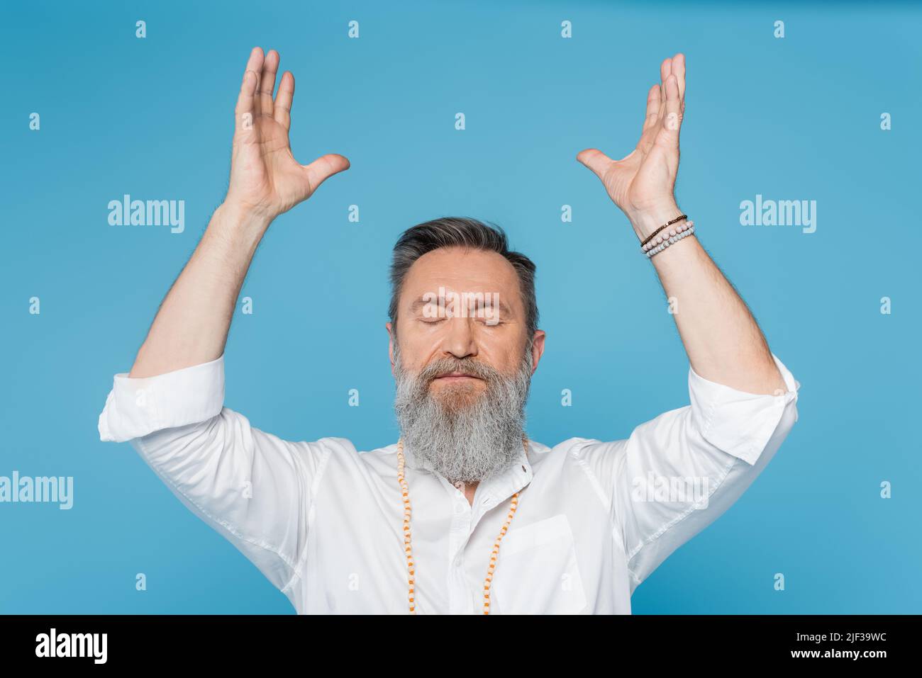 bearded guru man meditating with closed eyes and raised hands isolated ...