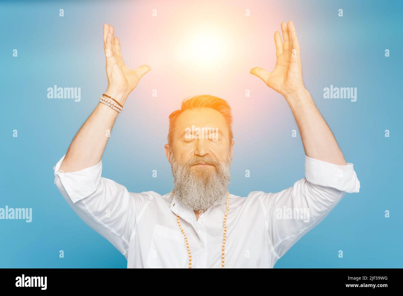 master guru meditating with closed eyes and raised hands near shining ...