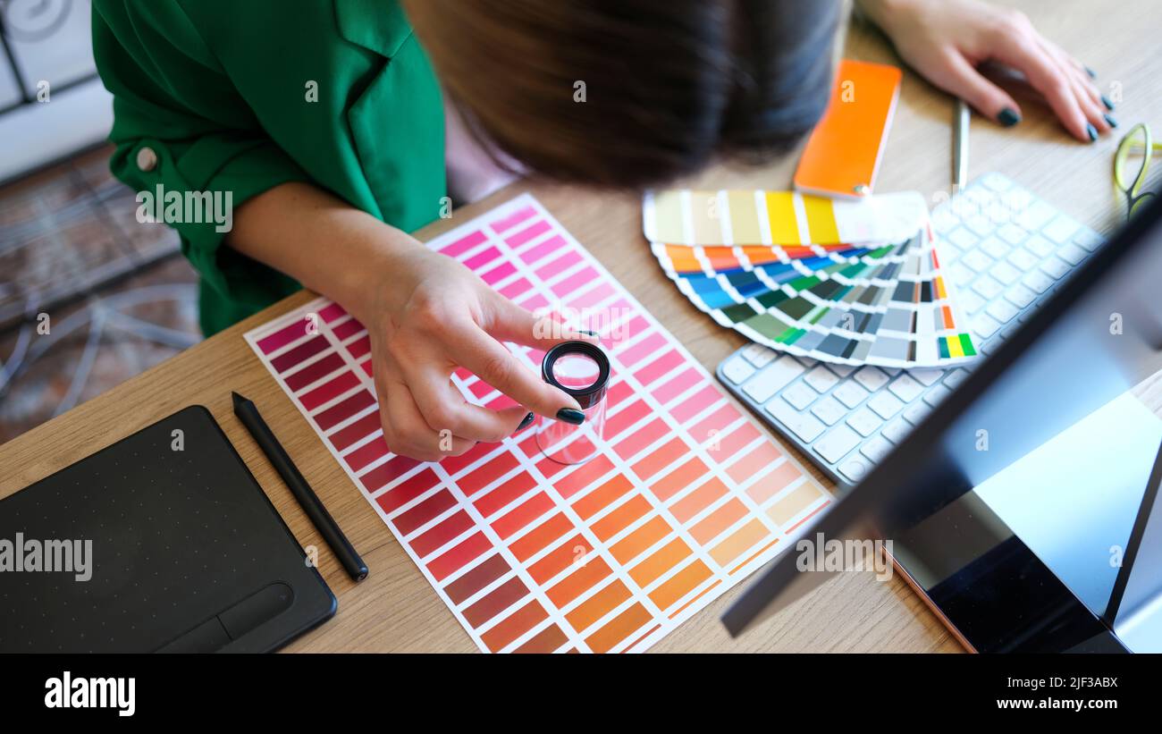 Woman chooses through magnifying glass color and shades on color ...