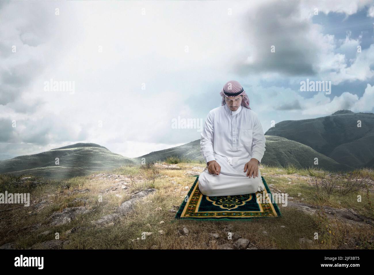Muslim man with keffiyeh with agal in praying position (salat) on the ...