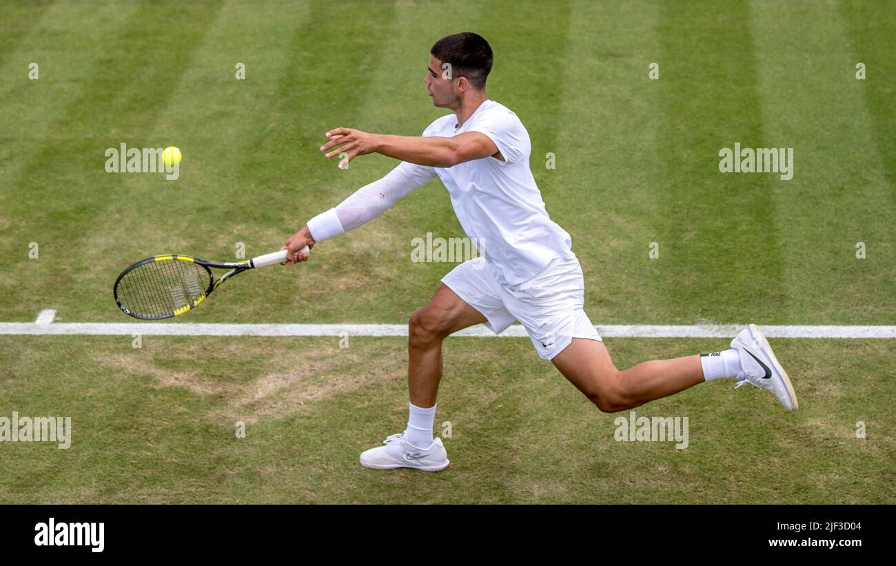 London, UK. 25th June, 2022. Carlos Alcaraz reaches to play a backhand ...