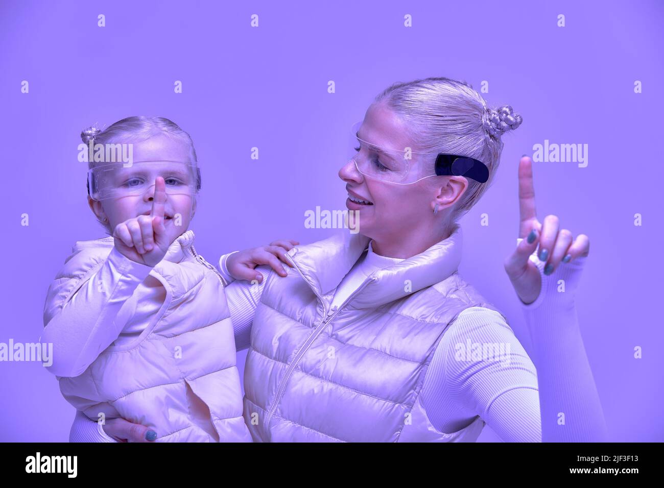 young woman with little girl wearing head mount display and futuristic ...
