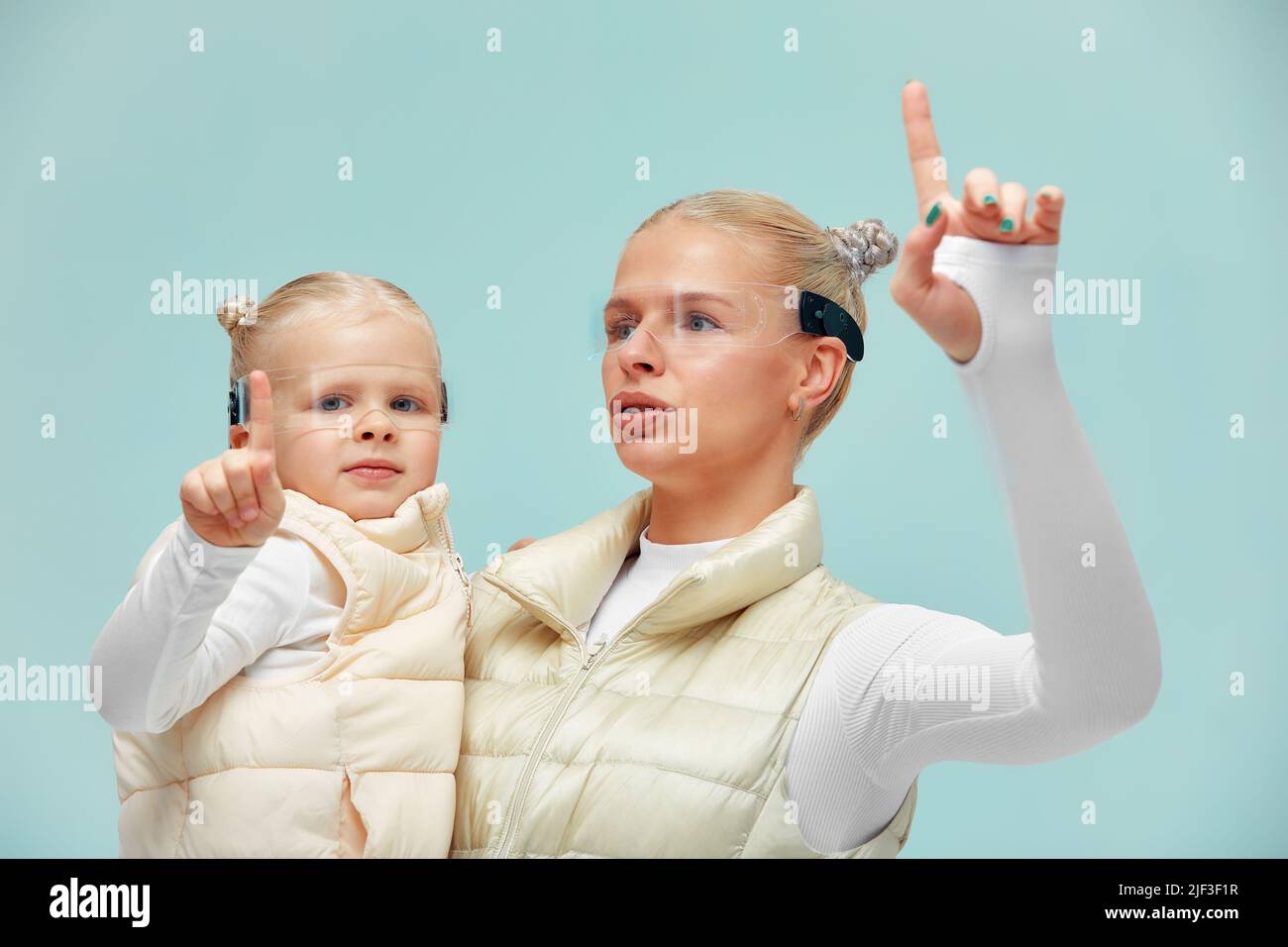 young woman with little girl wearing head mount display and futuristic ...