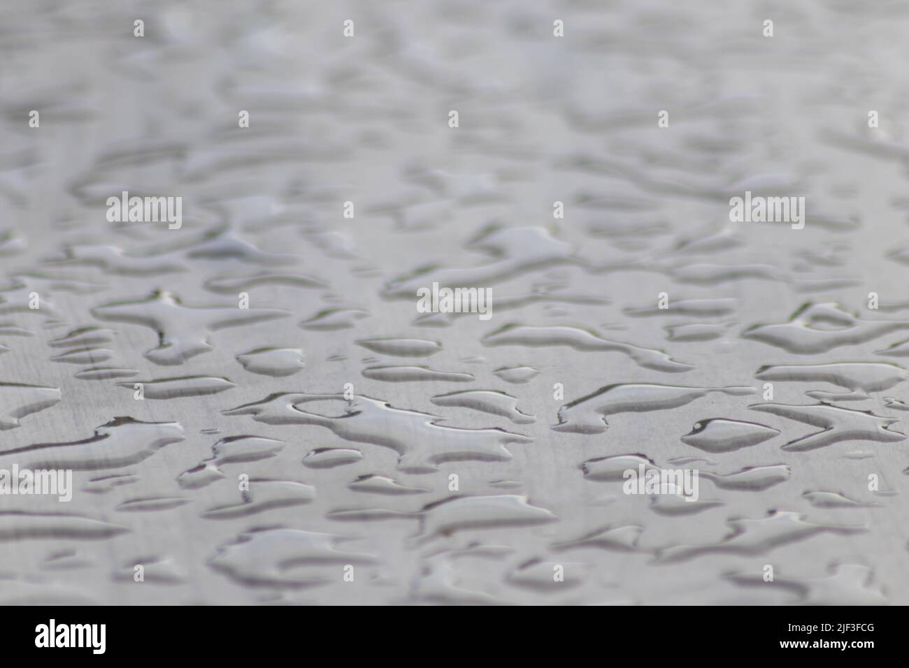 Many raindrops on a table surface on rainy day show pearls of water as ...