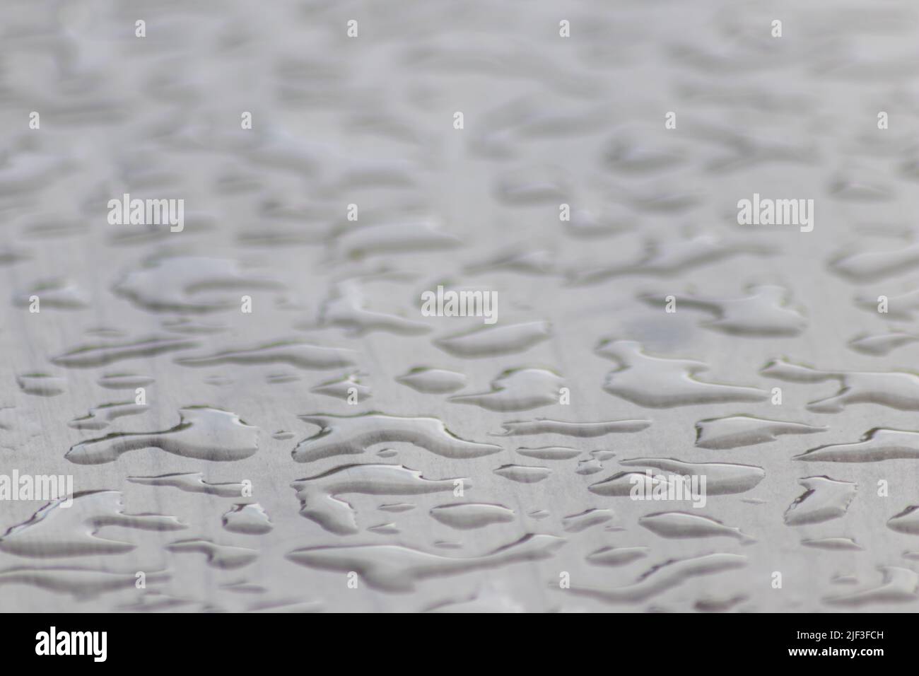 Many raindrops on a table surface on rainy day show pearls of water as ...