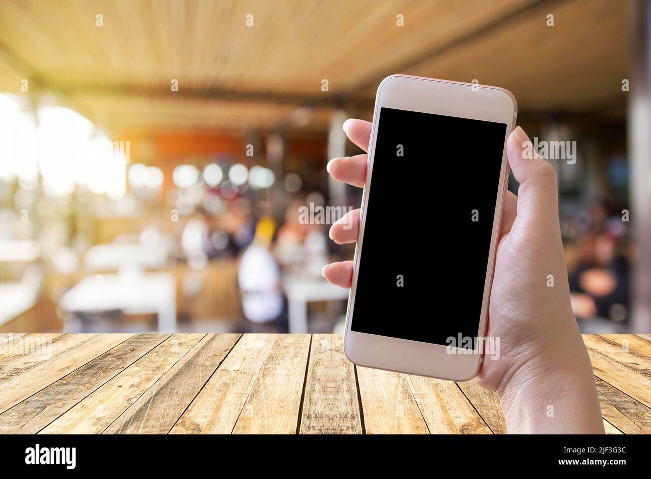 Hand holding mobile smart phone with office desk vintage wood working ...