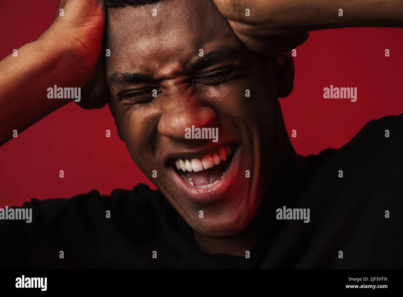 Young black man with headache holding his head while screaming isolated ...