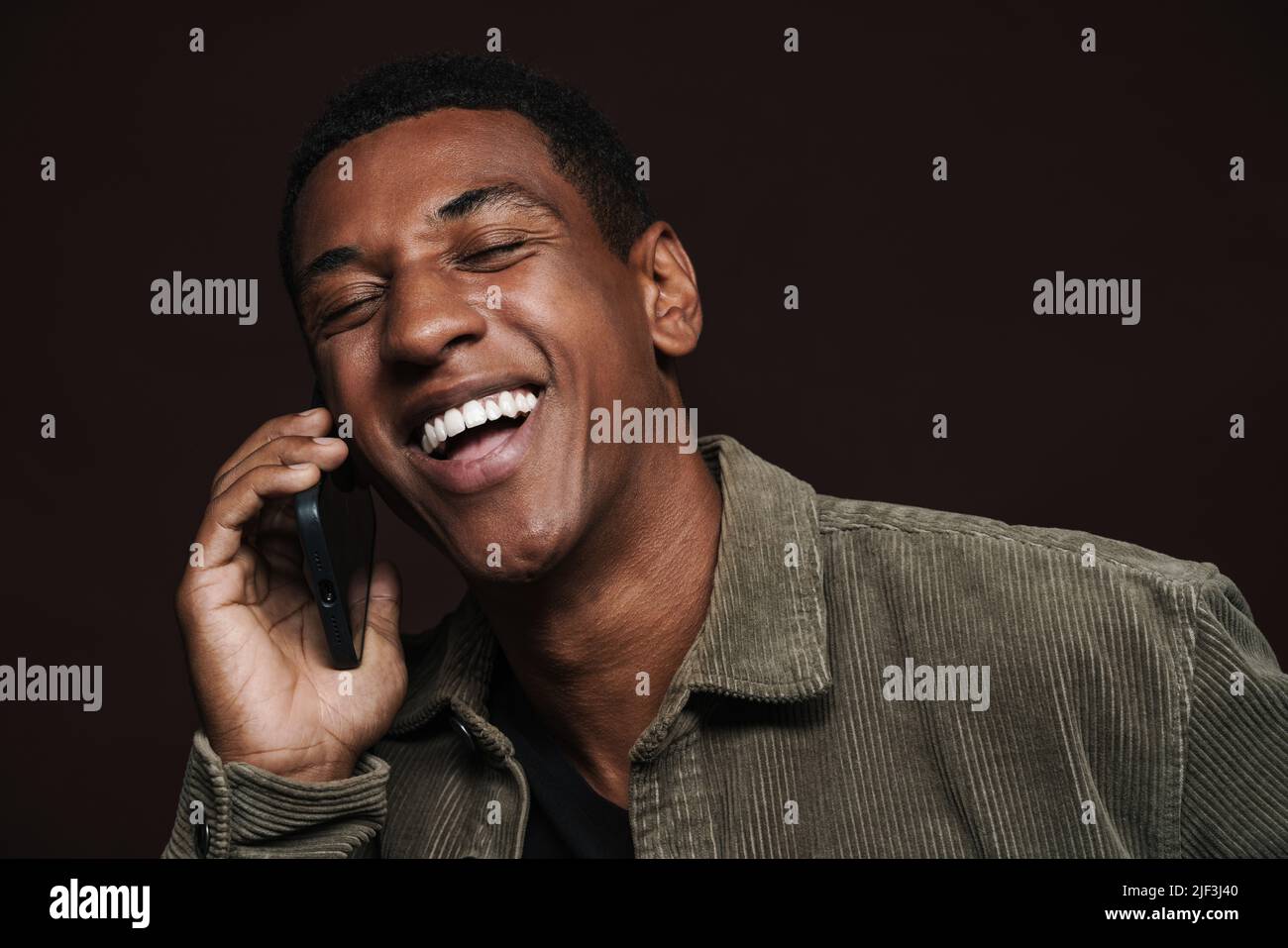 Young black man laughing while talking on mobile phone isolated over ...