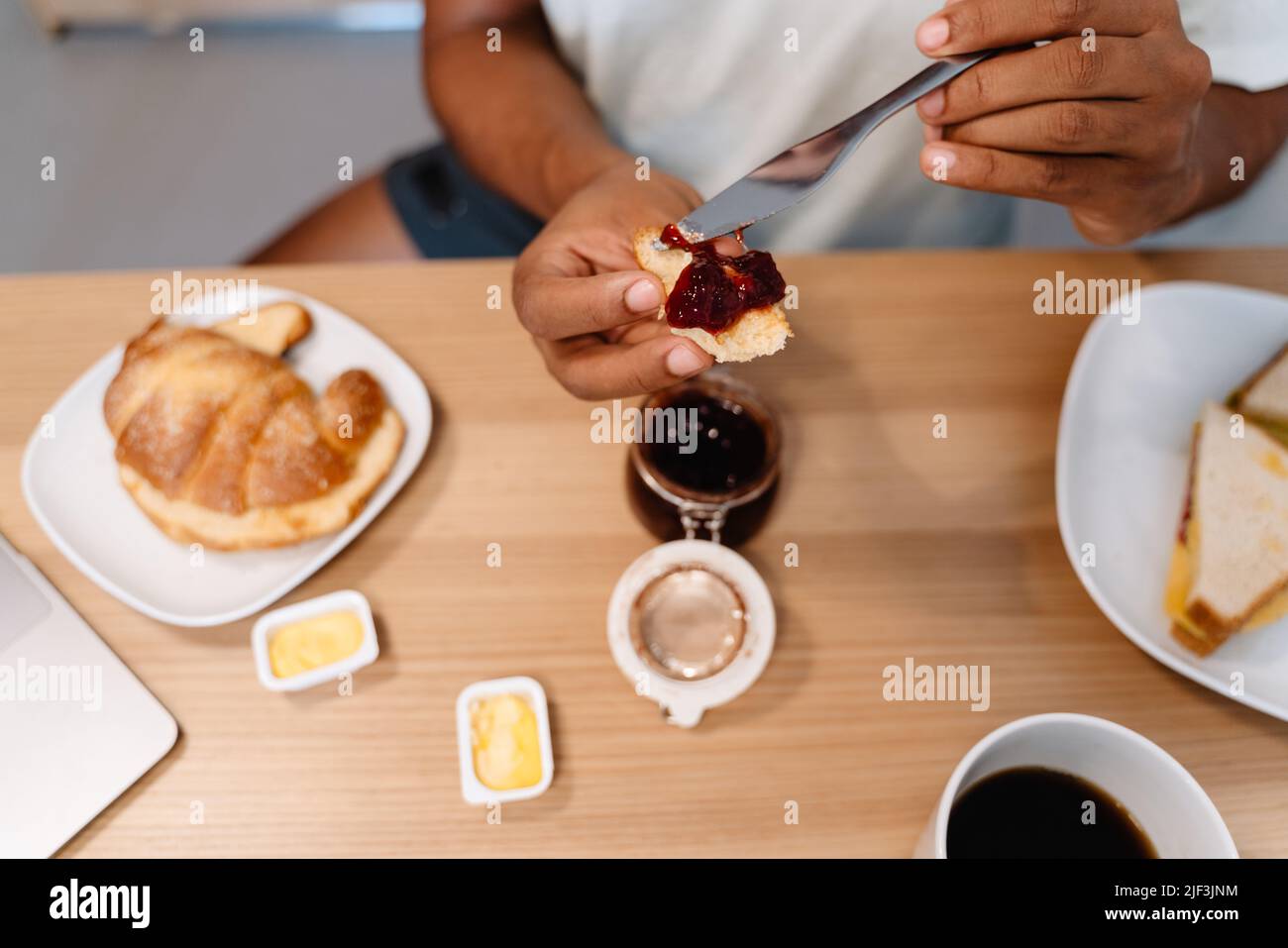 Black man eating croissant with jam while having breakfast in hotel ...