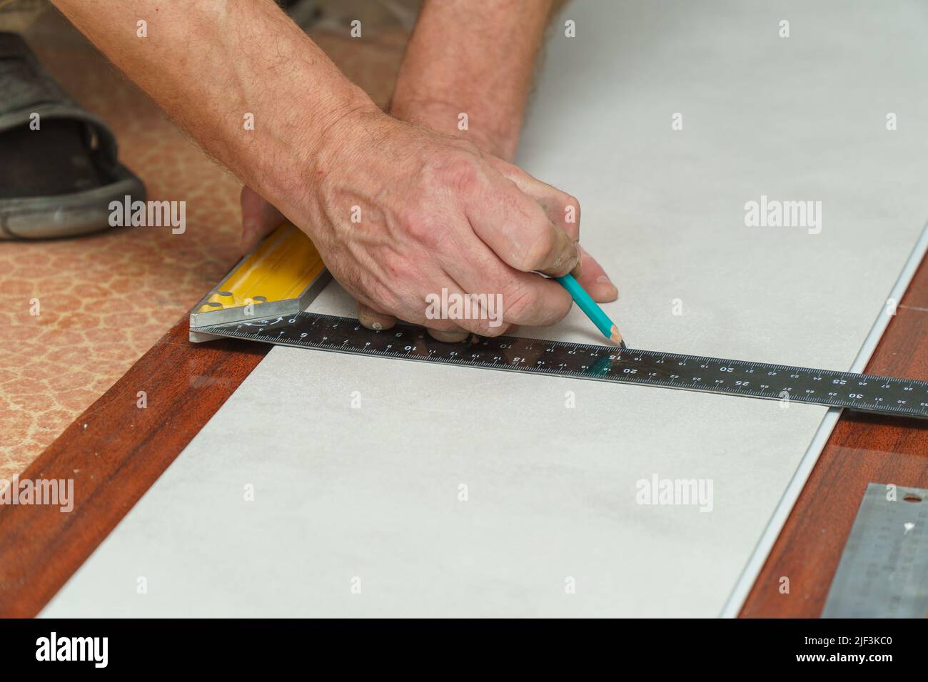 The worker marks the plastic panel with a pencil and tape measure or ...