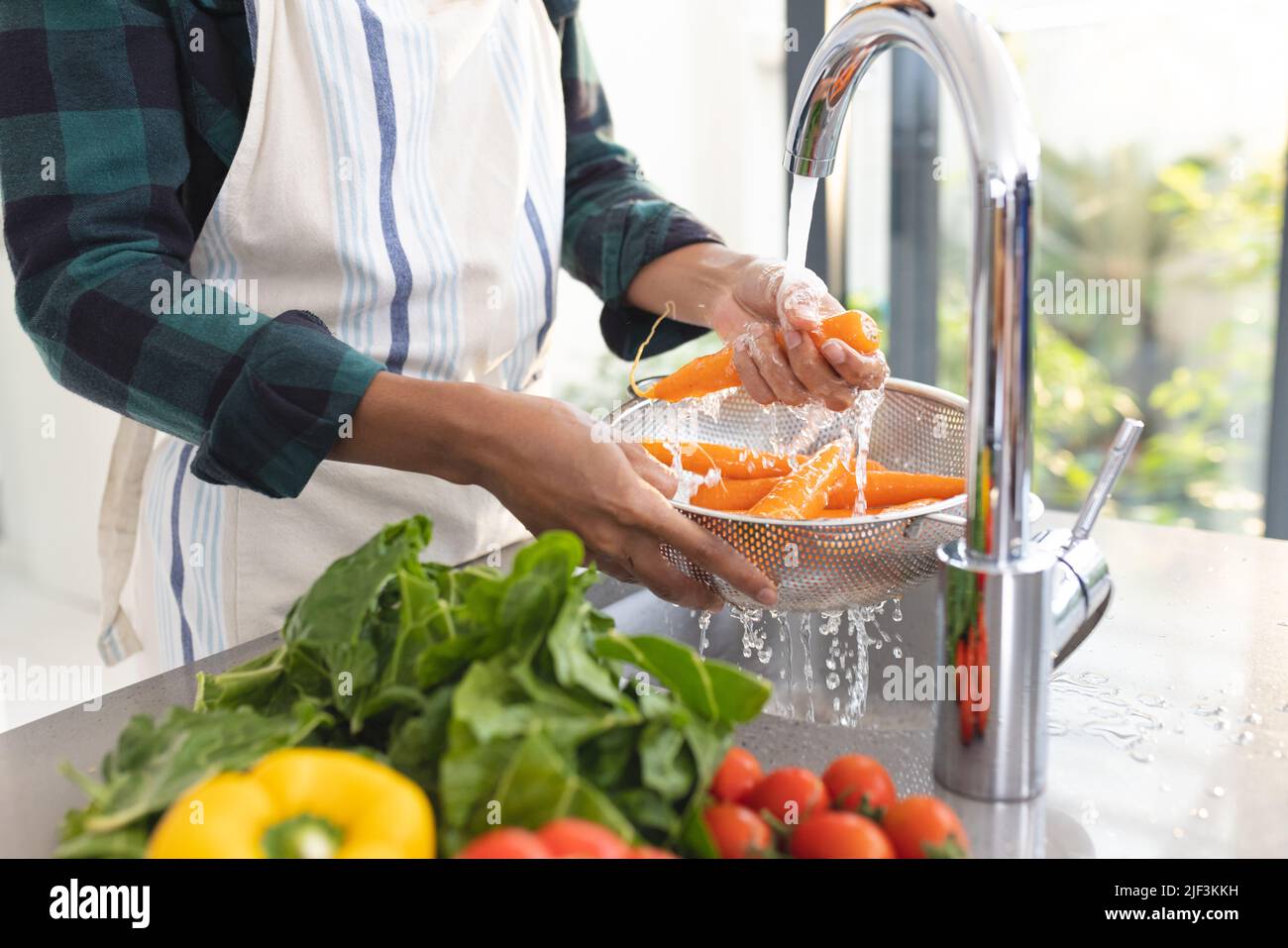 Midsection of african american mid adult man wearing apron cleaning ...