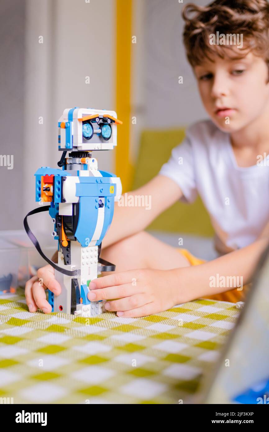 Kid collects robot from plastics details and programmed on tablet ...