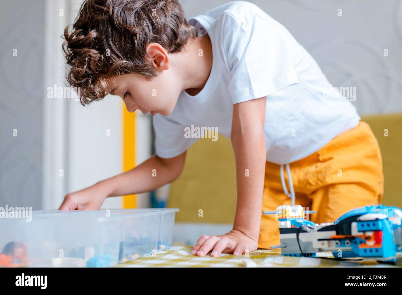 Kid collects robot from plastics details and programmed on tablet ...