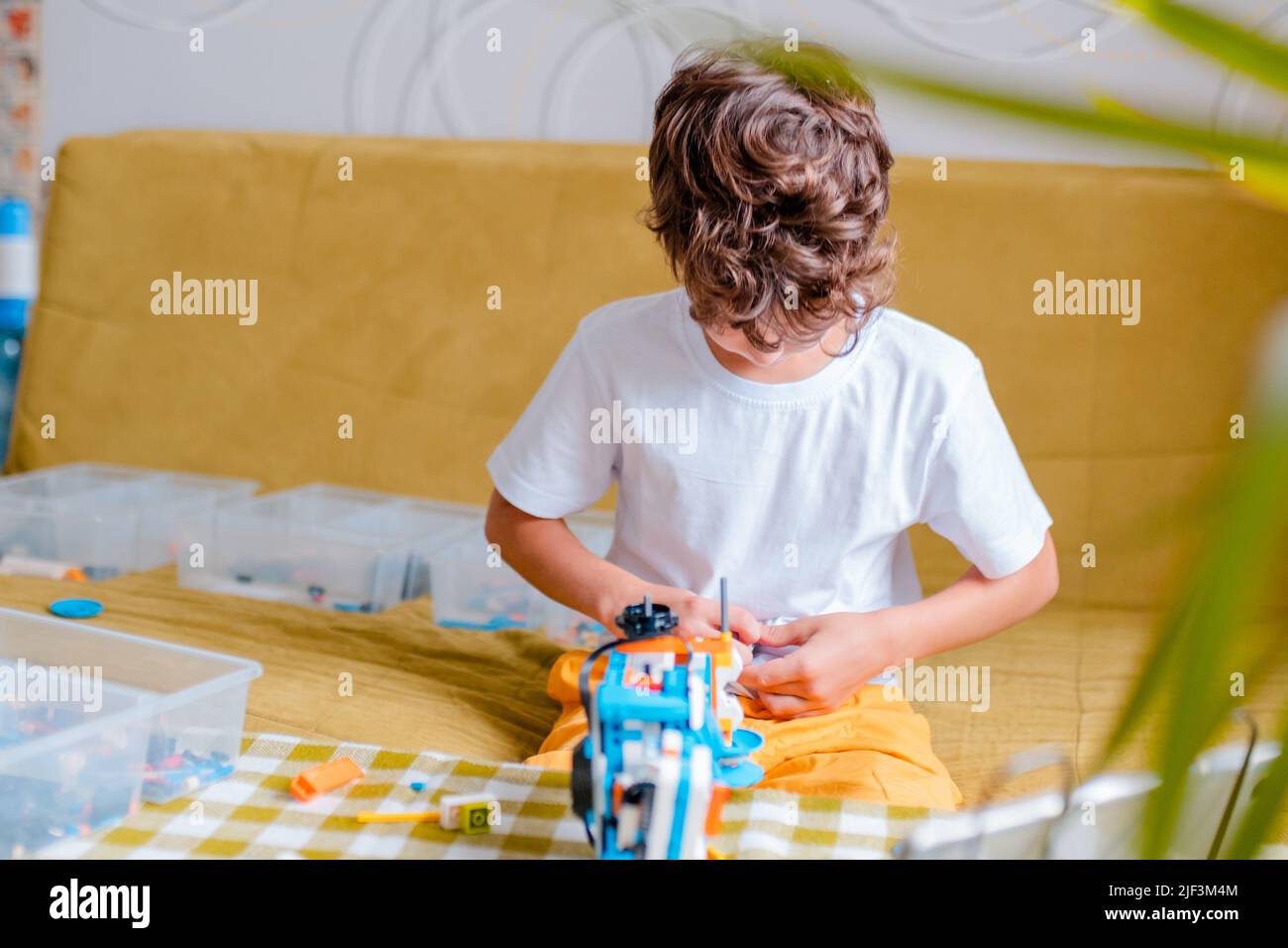 Kid collects robot from plastics details and programmed on tablet ...
