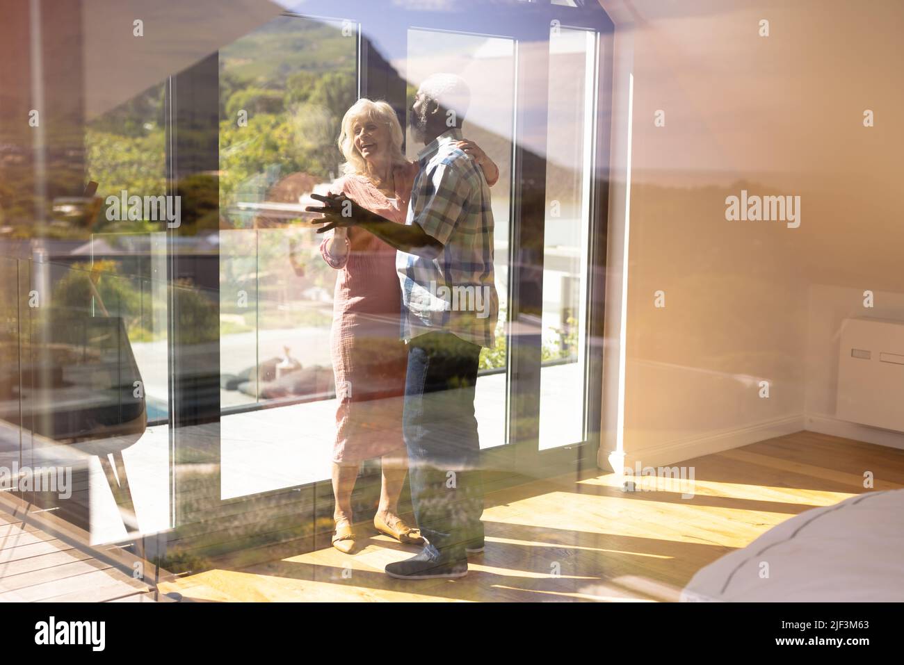 Happy multiracial senior friends dancing by window in nursing home seen ...