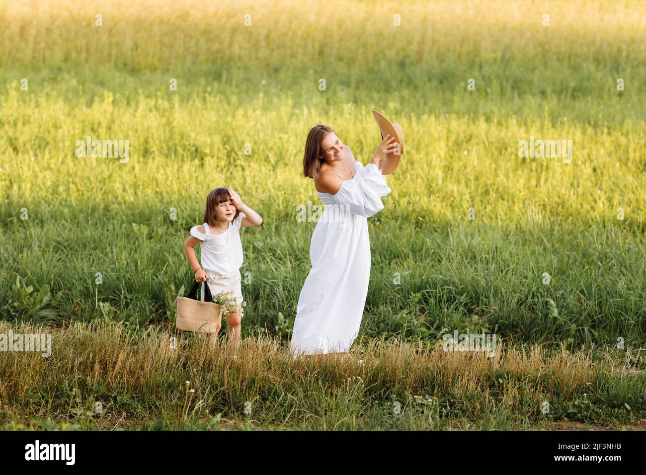 Joyful young mother playing catch together with child daughter in green ...