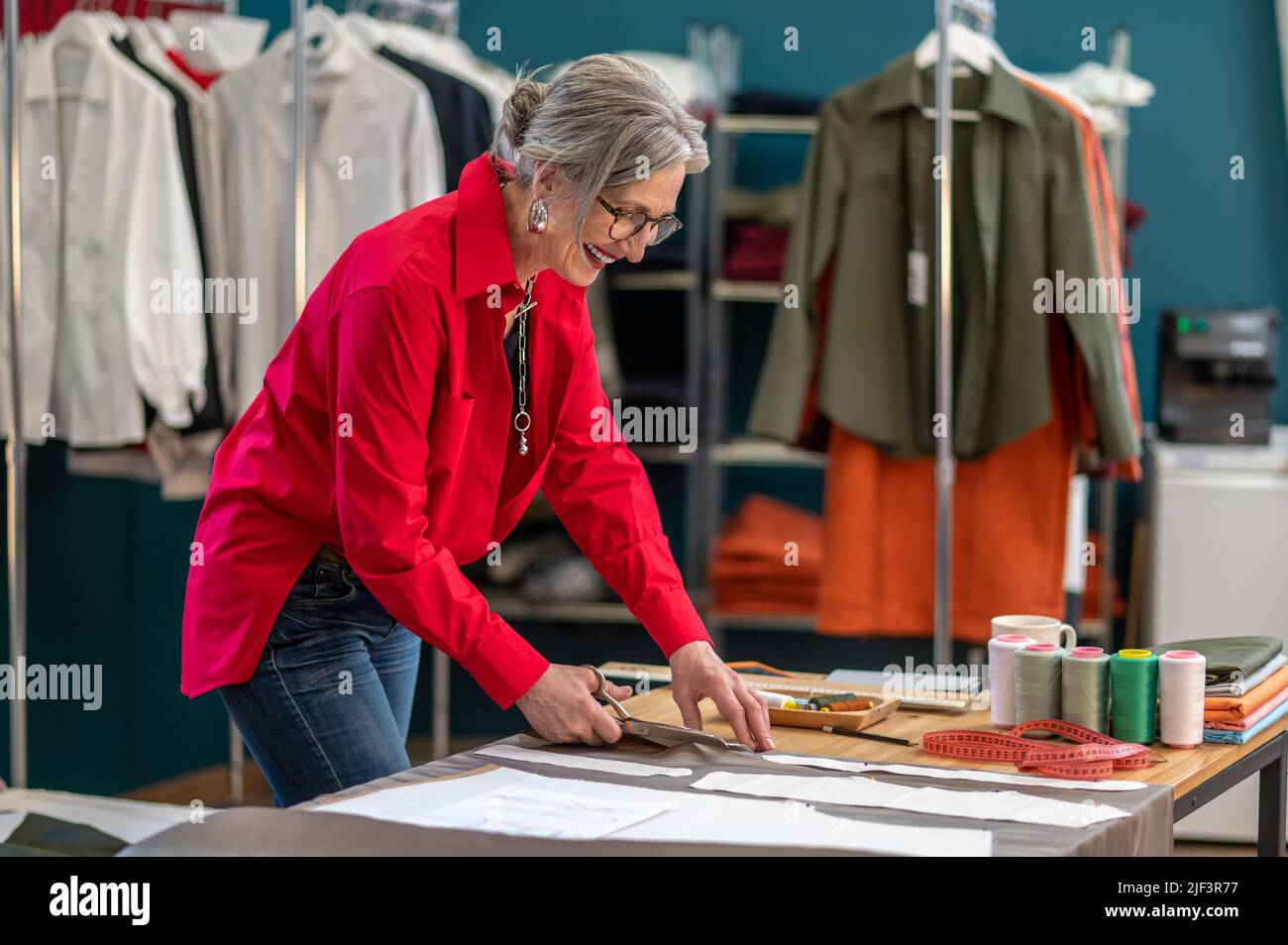 Joyful woman cutting pattern standing leaning over table Stock Photo ...