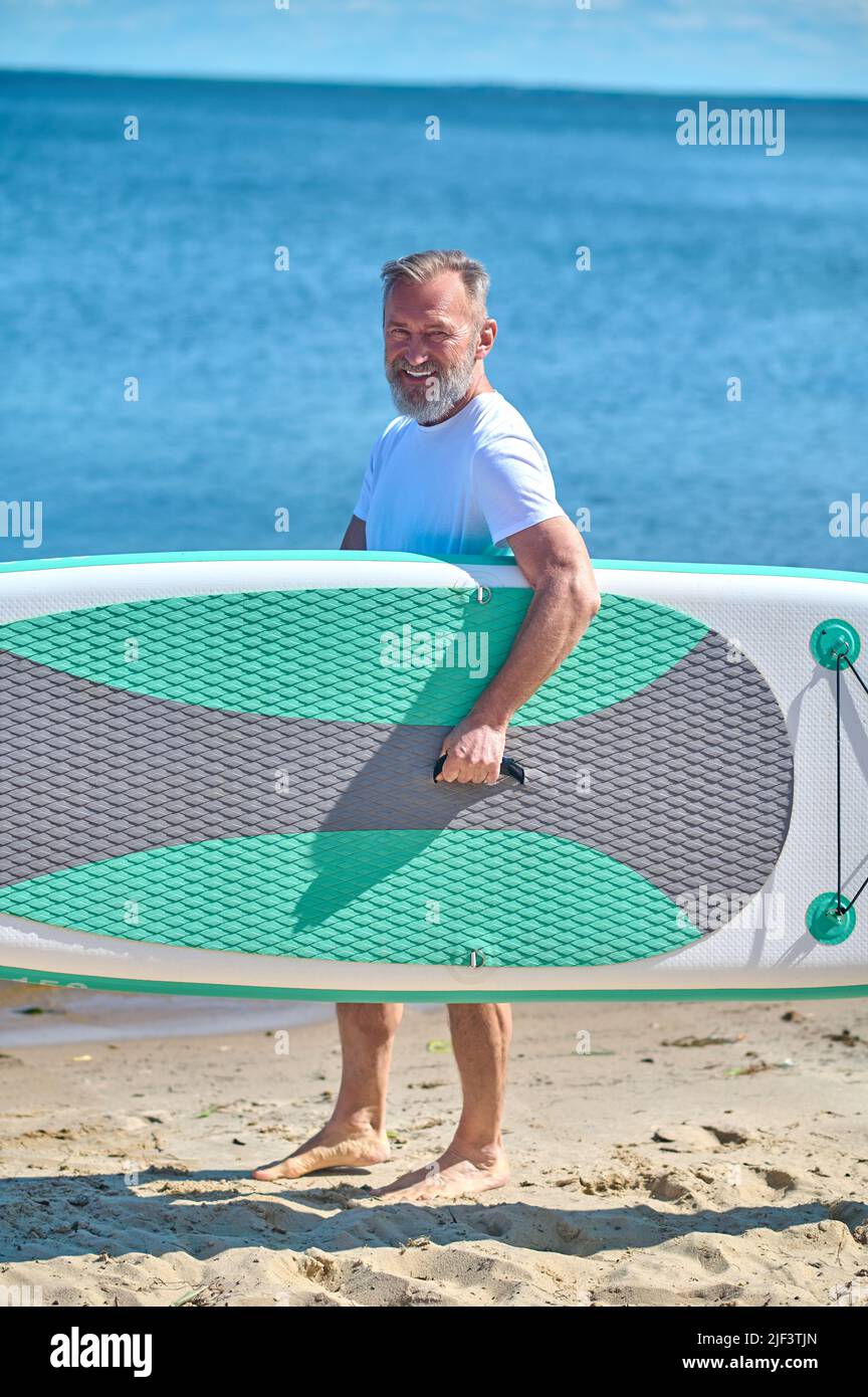 Man carrying surfboard smiling at camera Stock Photo - Alamy
