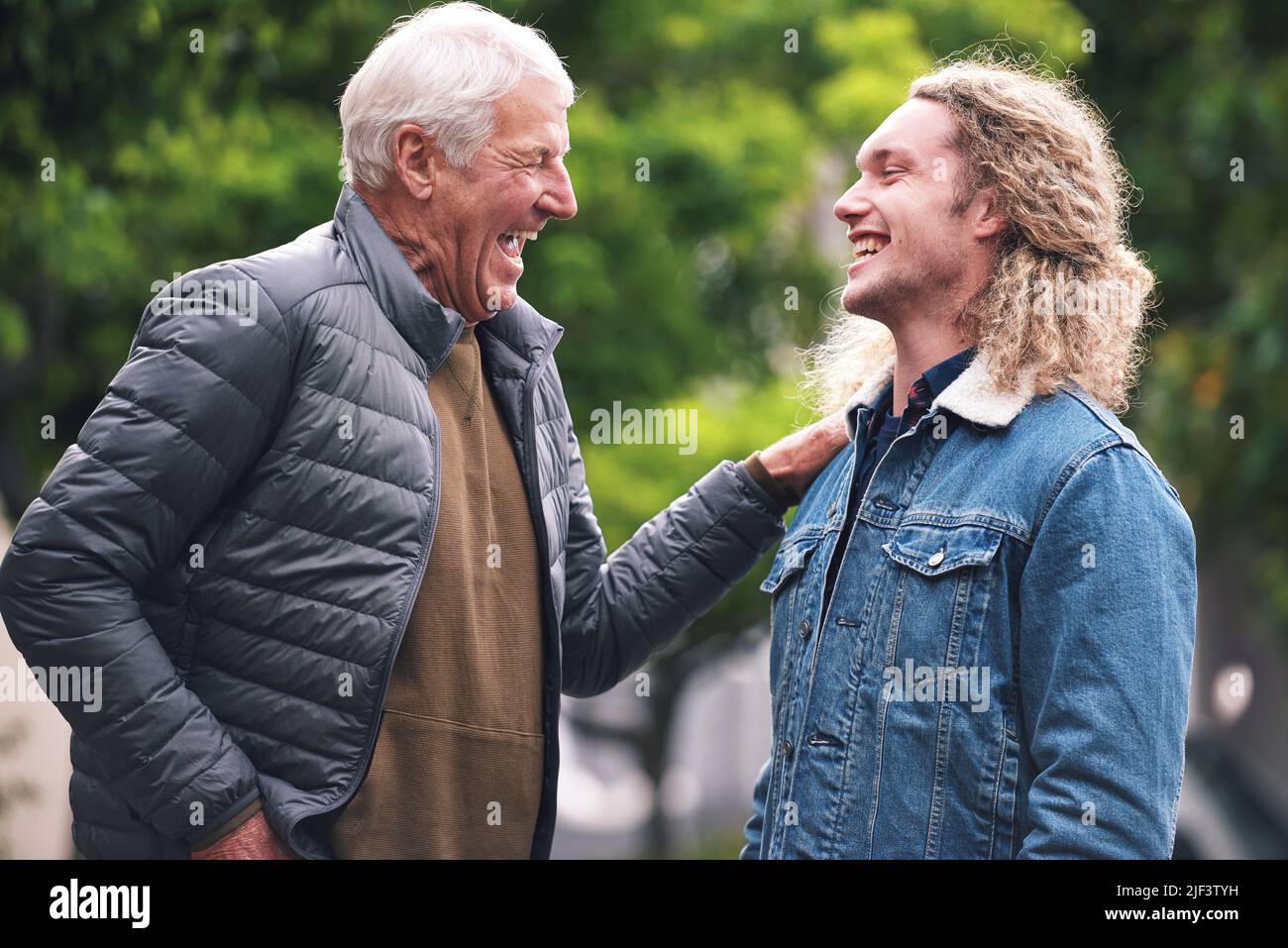 A mature man talking to his young son and laughing while touching his ...