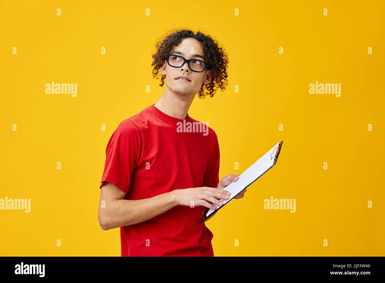 Thinking myopic young student man in red t-shirt funny eyewear holds ...