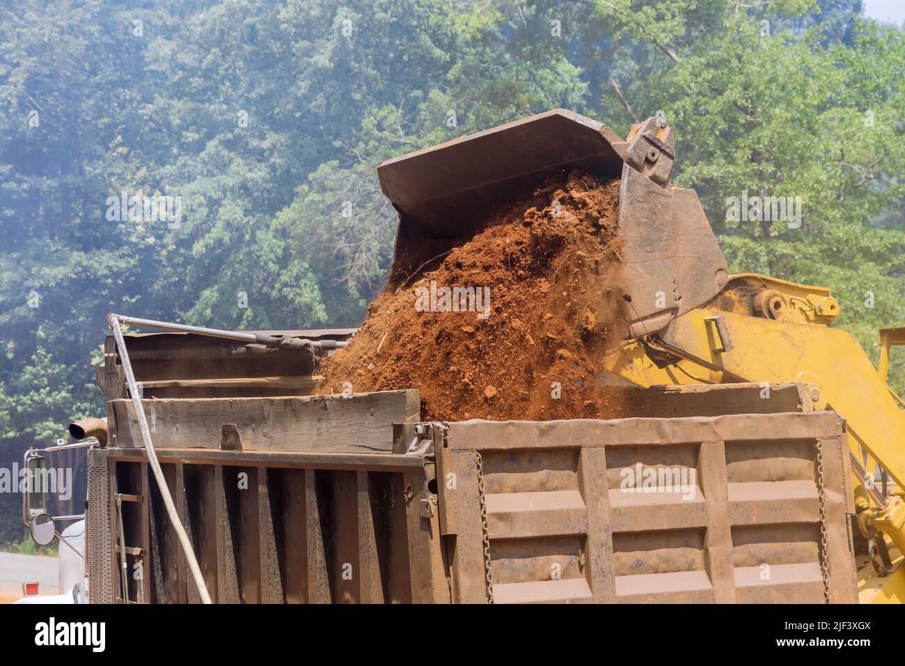 Heavy construction equipment load earth into dump truck using ...