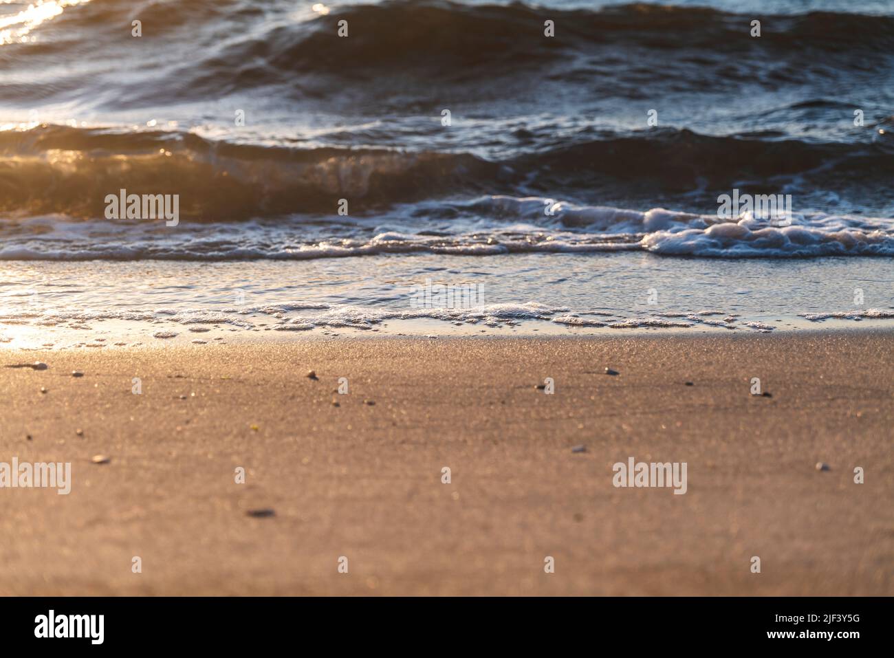 Beautiful sunset reflection on a waves on the beach Stock Photo - Alamy