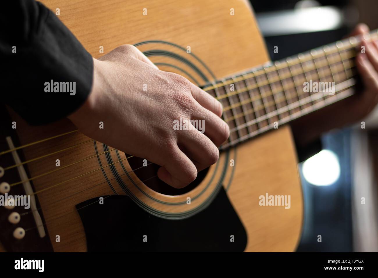 Hands of a musician playing an acoustic guitar with metal strings ...