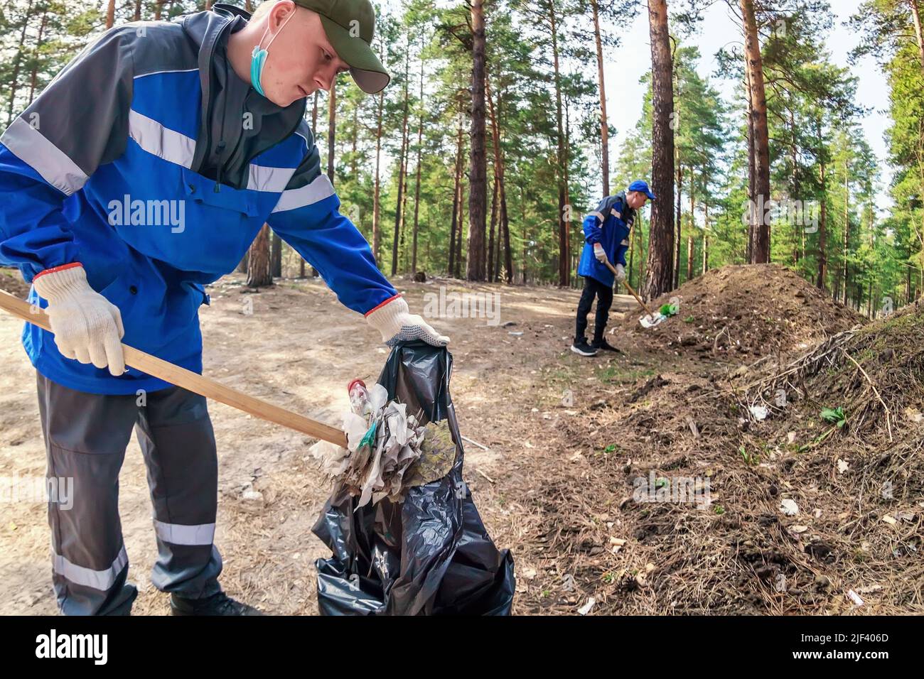 Man in overalls collects garbage and waste in forest. Ecological ...
