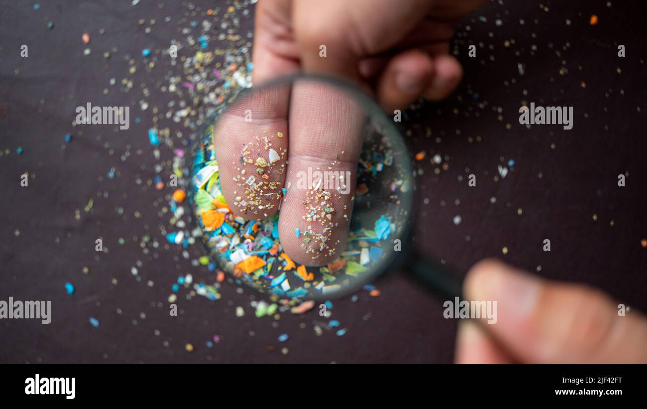 Close-up on micro plastic particles on the fingers under a magnifying ...