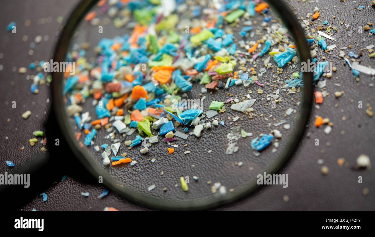 Close-up on micro plastic particles under a magnifying glass. Concept ...