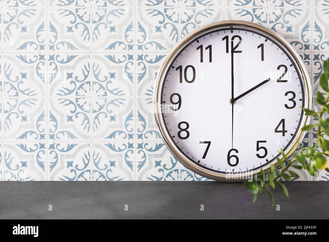 Classic, round wall clock on a marble shelf on a tile wall with home ...