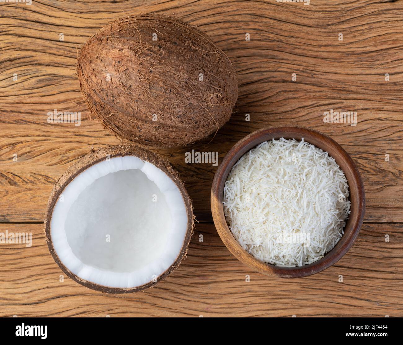 Grated coconut flakes in a bowl with fruit over wooden table Stock ...