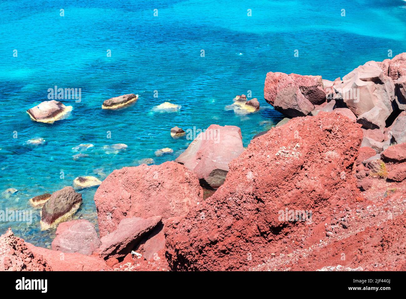 Crystal clear water down of the volcanic red cliffs of Akrotiri beach ...