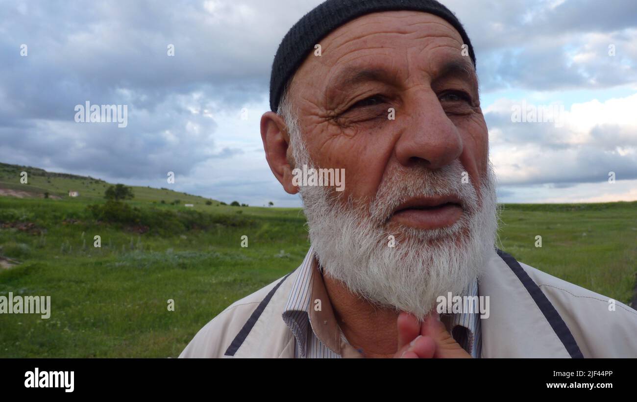 Smiling elderly man with a muslim beard and mustache wearing a brown ...
