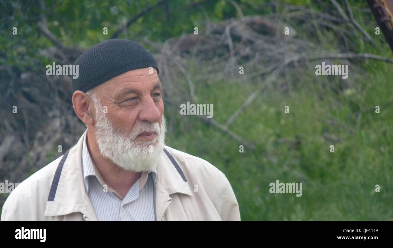 Smiling elderly man with a muslim beard and mustache wearing a brown ...