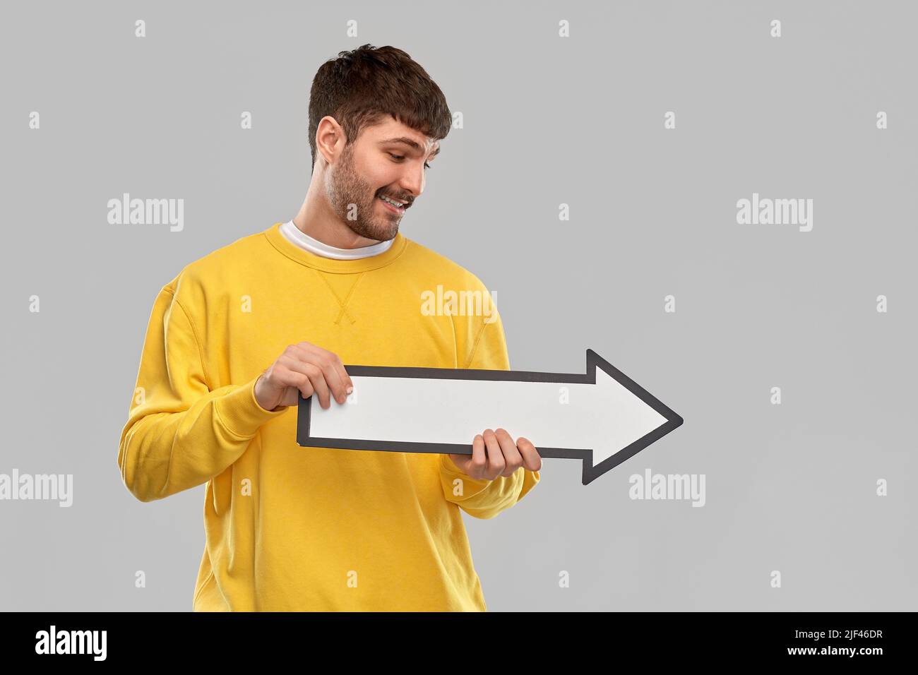 smiling man holding big arrow pointing to right Stock Photo - Alamy