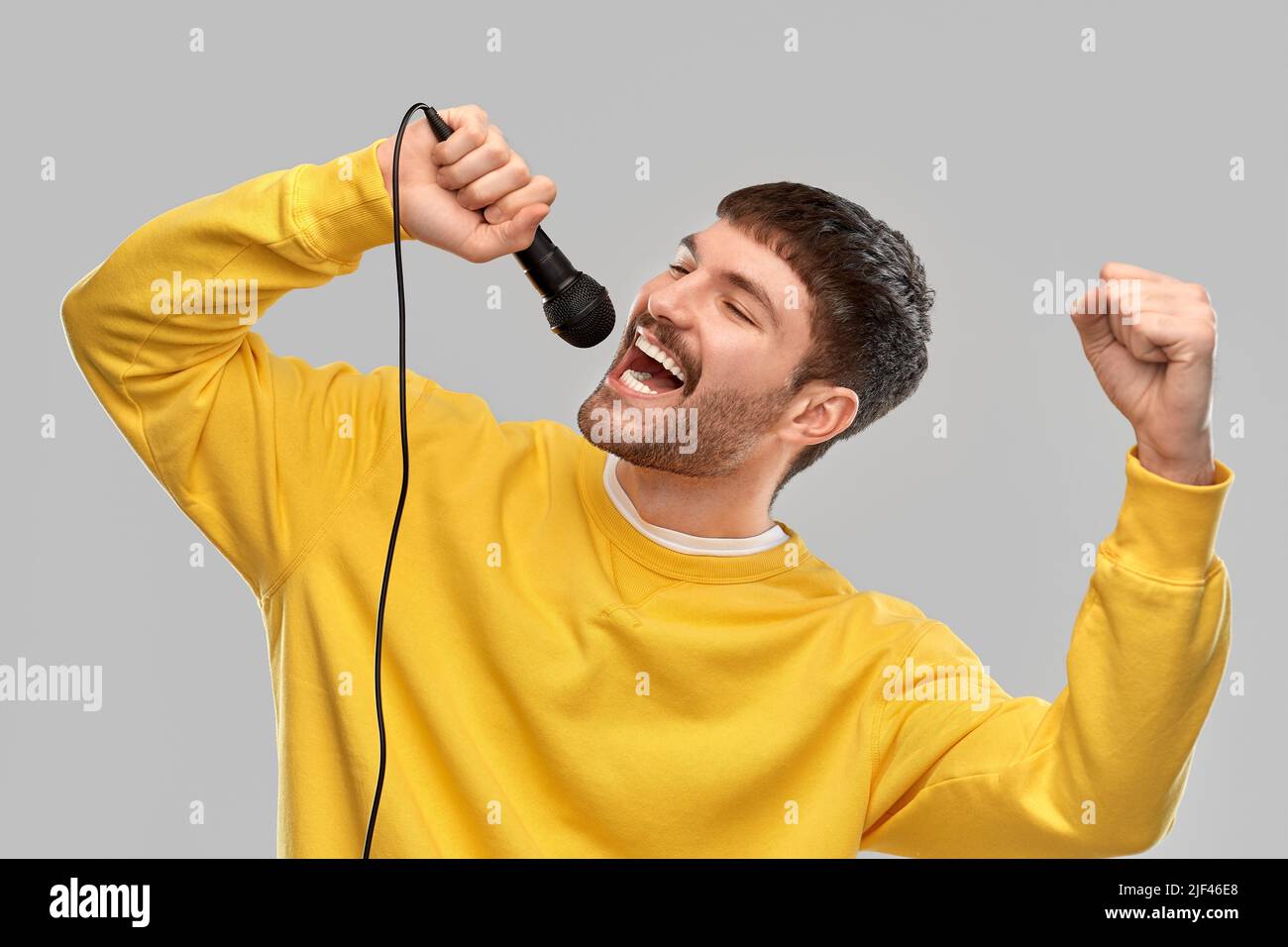 man in yellow sweatshirt with microphone singing Stock Photo - Alamy