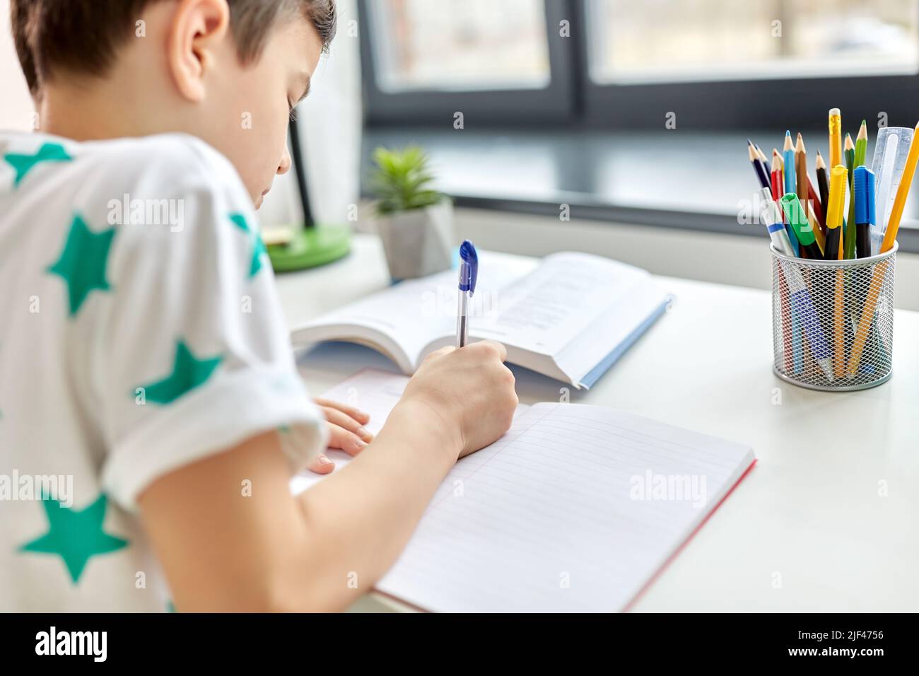 close up of boy writing to notebook at home Stock Photo - Alamy