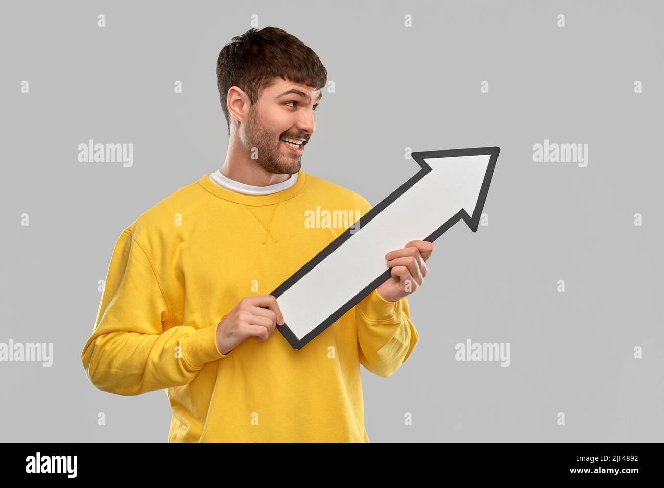 smiling man holding big arrow pointing to right Stock Photo - Alamy