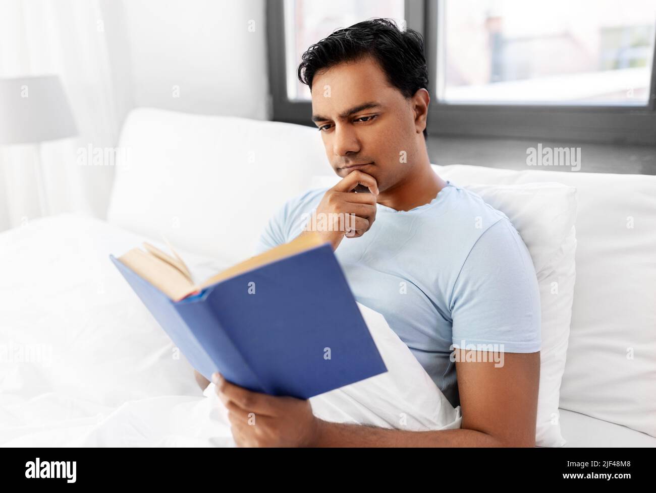 indian man reading book in bed at home Stock Photo - Alamy