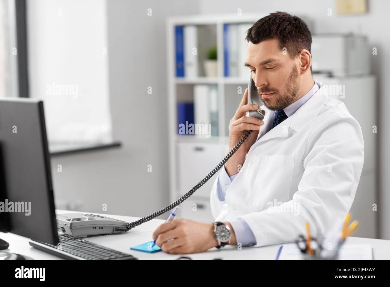 male doctor calling on desk phone at hospital Stock Photo - Alamy