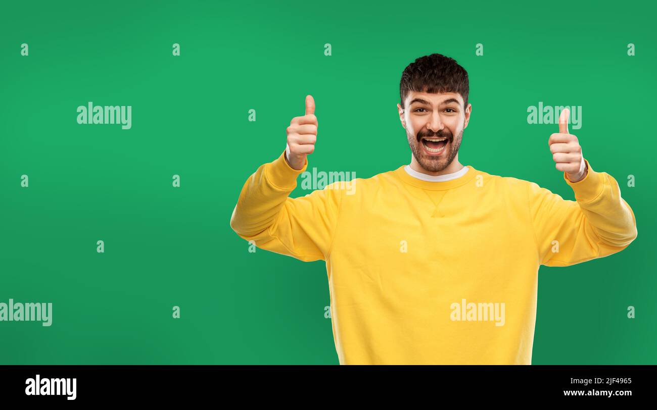happy man showing thumbs up over green background Stock Photo - Alamy
