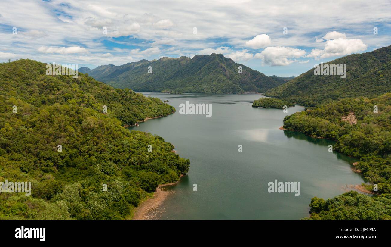 Mountain lake among hills with tropical vegetation and blue sky with ...