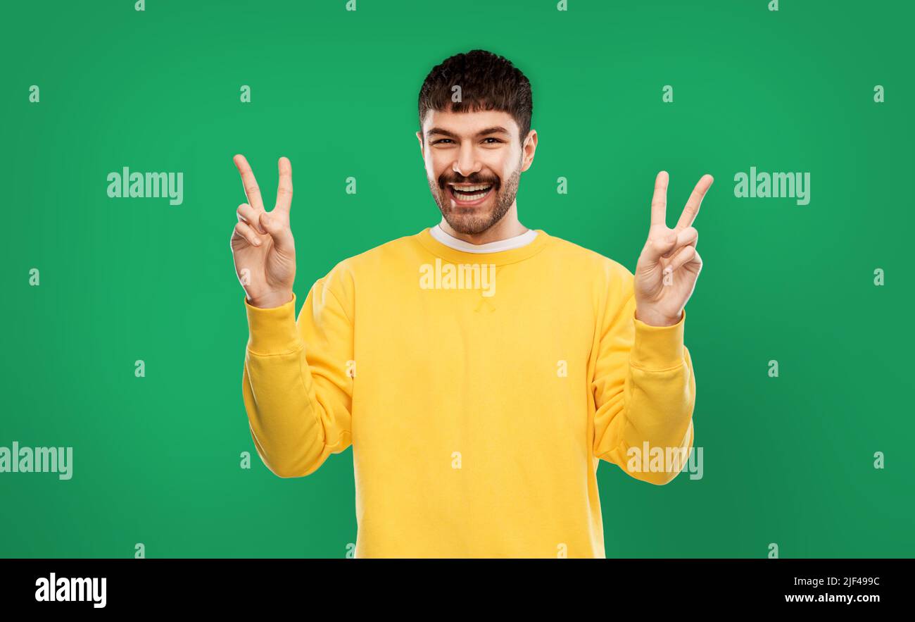 young man showing peace over grey background Stock Photo - Alamy